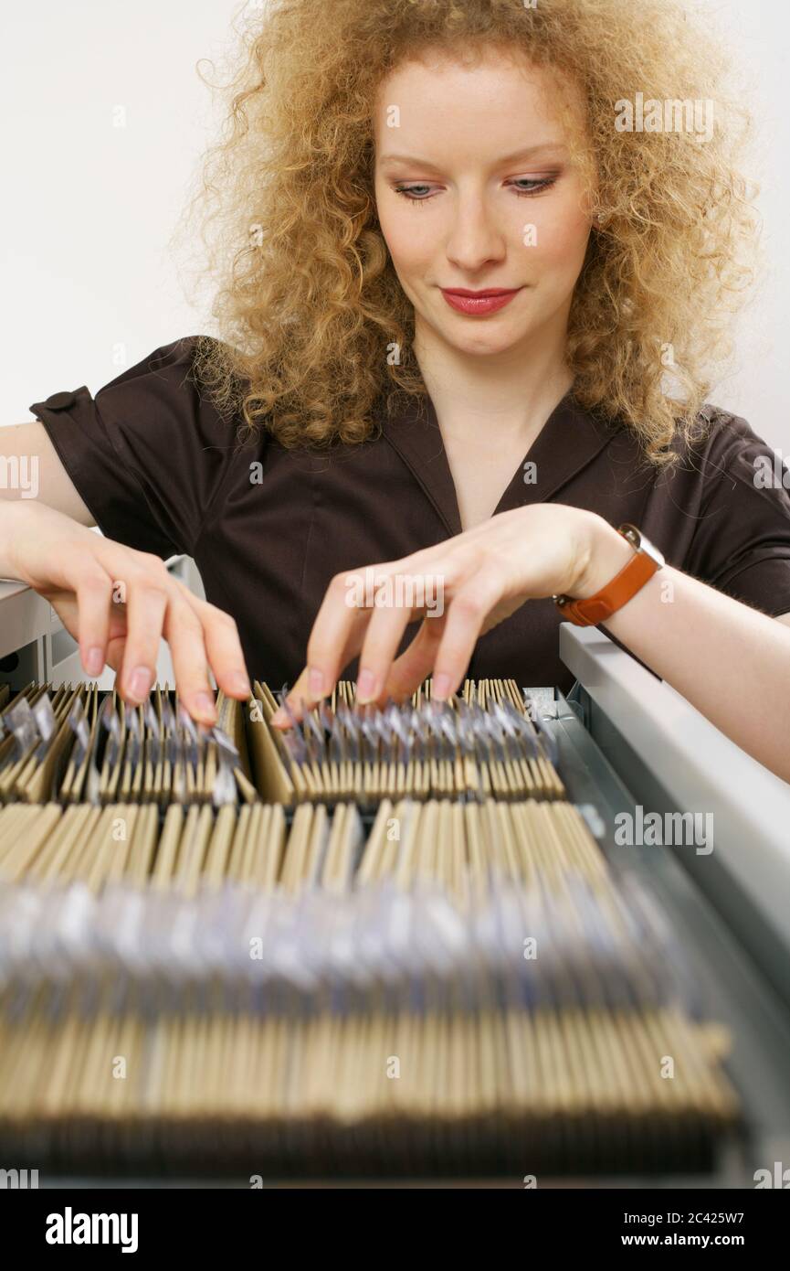 Young woman is looking out files Stock Photo - Alamy