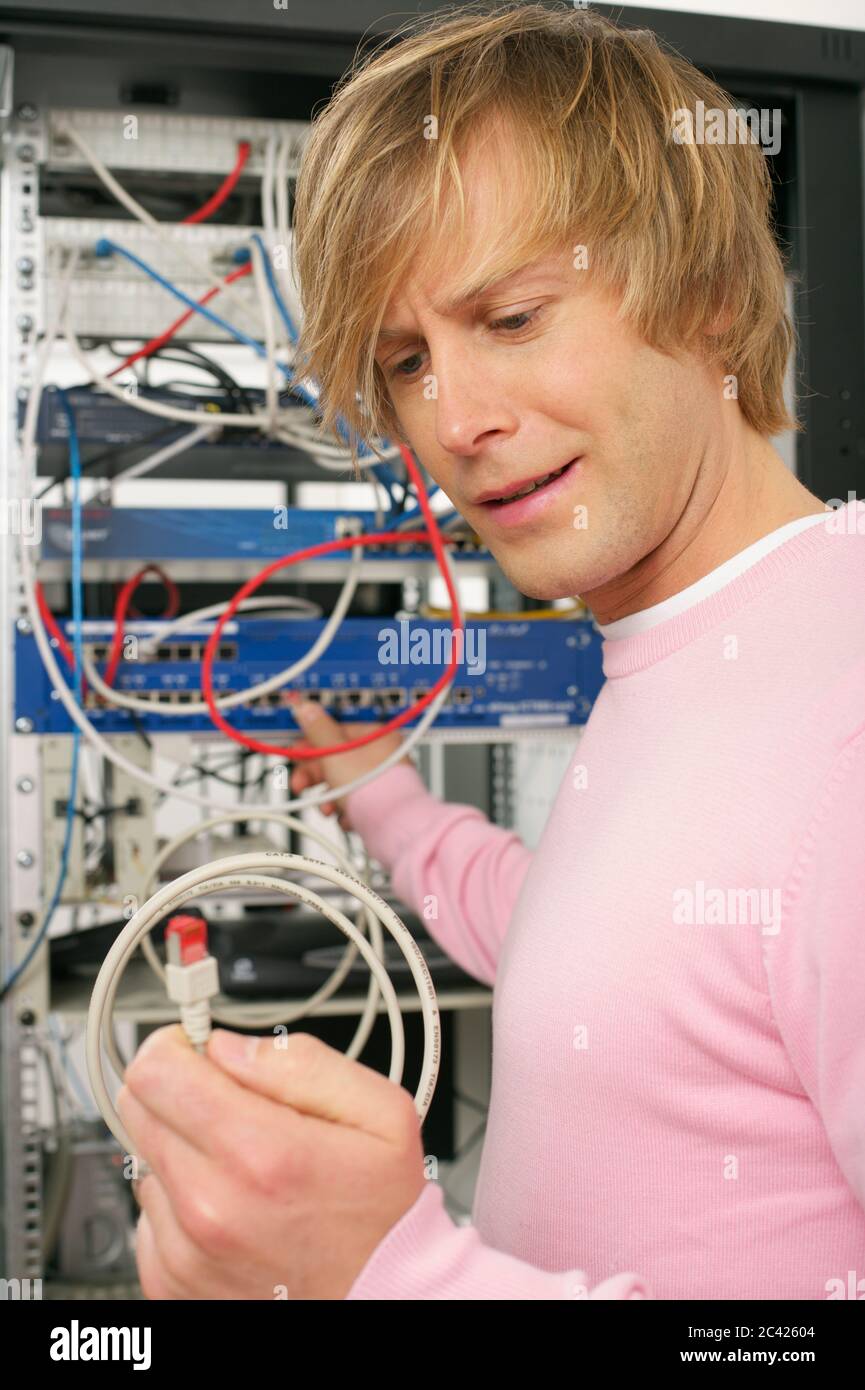 Young man connects network cables to a server Stock Photo - Alamy