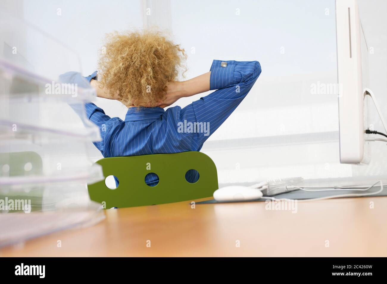 Young woman sitting in the office, leaning back Stock Photo - Alamy