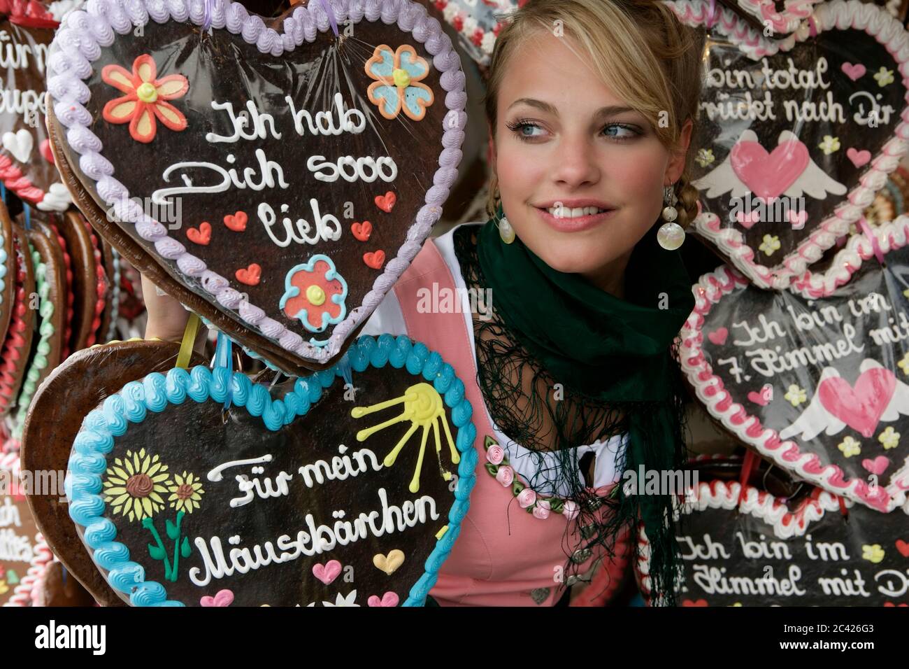 Young woman sticks her head between hanging gingerbread hearts ...