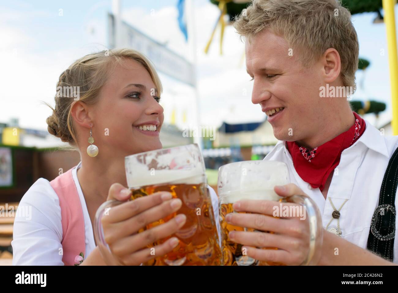 Young woman and young man in traditional clothes clink glasses with ...