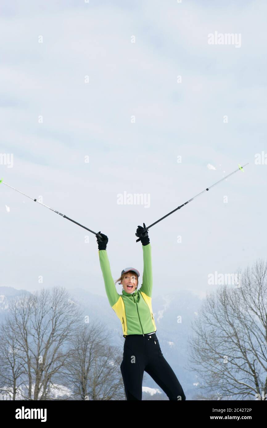 Woman cheering with ski poles Stock Photo - Alamy