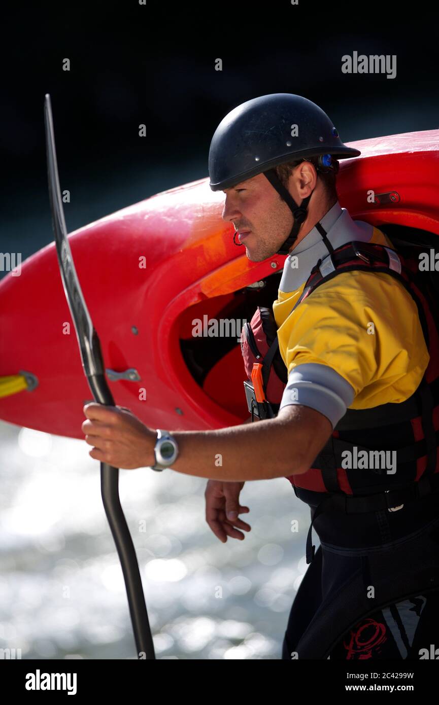 Young man carries a kayak and oar - protective clothing - adventure ...