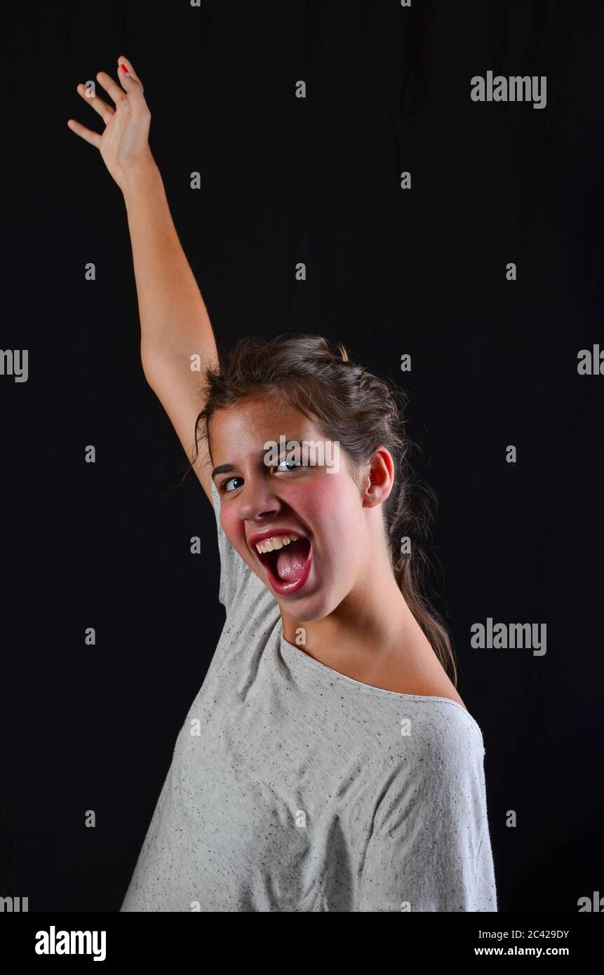 Cheerful teenage girl, shouting loudly to express joy, studio shot ...