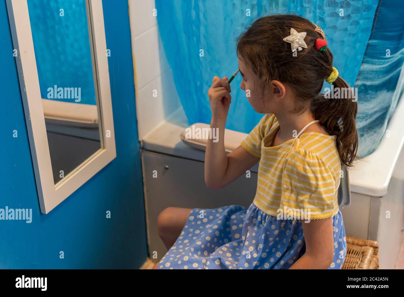 A young girl from poor deprived family is entertaining herself by face ...