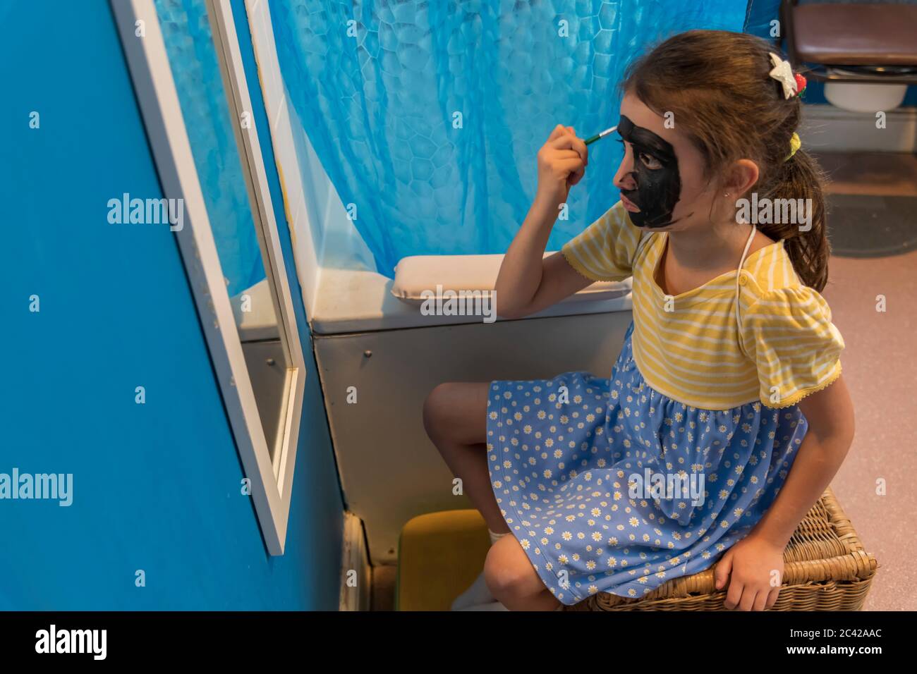 A young girl from poor deprived family is entertaining herself by face ...