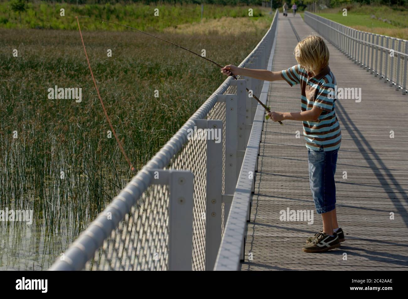Boy stands on a bridge and fishes Stock Photo - Alamy