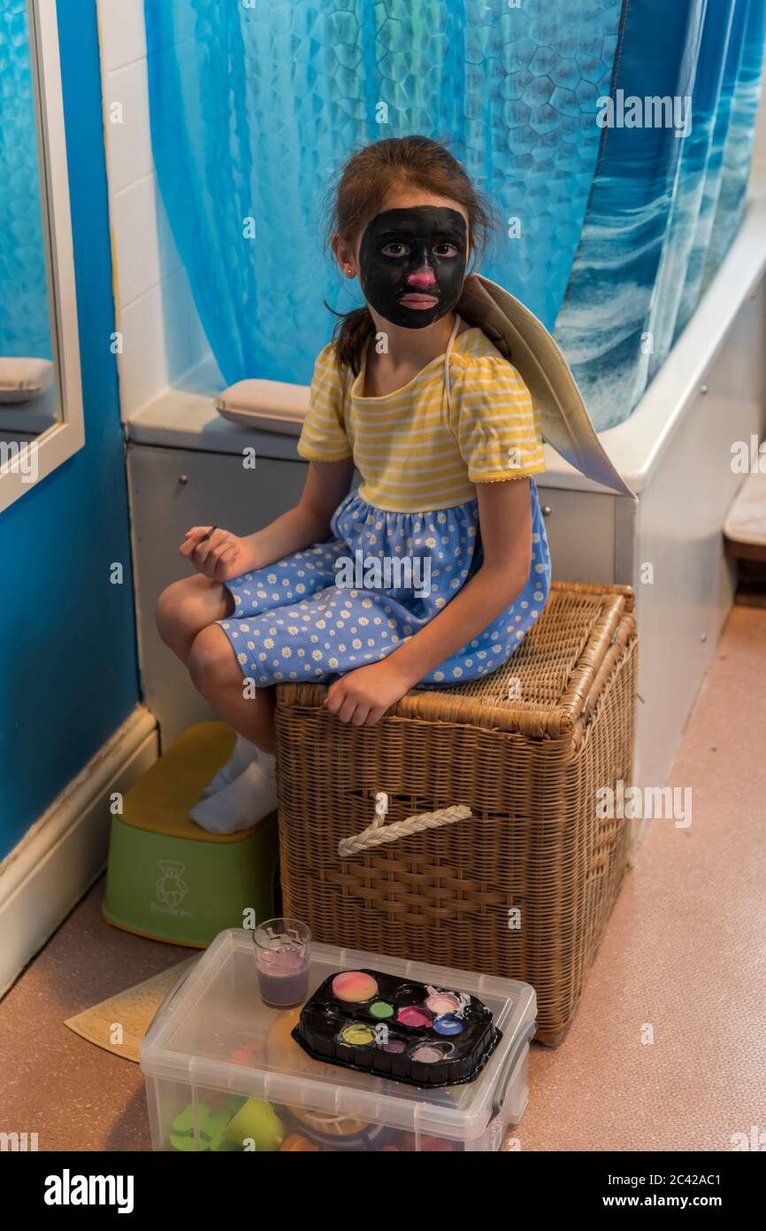 A young girl from poor deprived family is entertaining herself by face ...