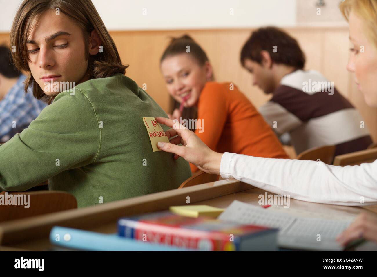 Girl sticks a note on a boy's back - prank - classroom Stock Photo - Alamy