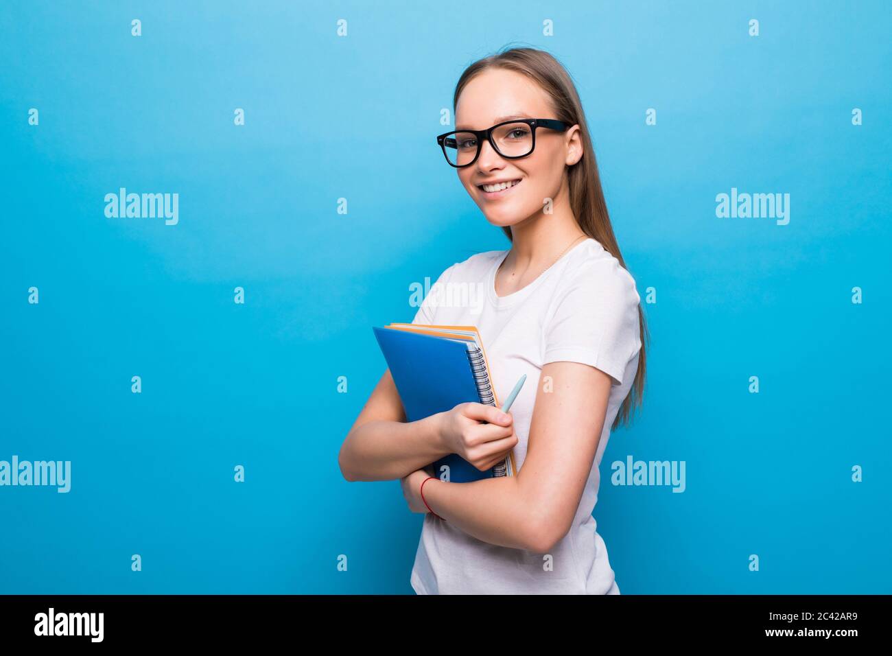 Beautiful smart young girl reading book isolated on the blue background ...