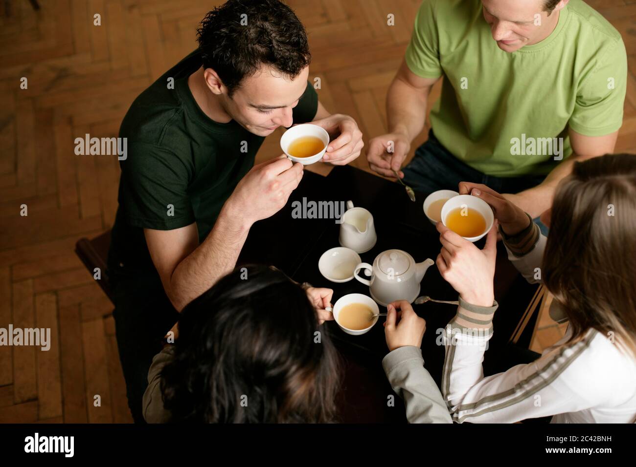 Four young people drink tea together at a table - interior - friends ...
