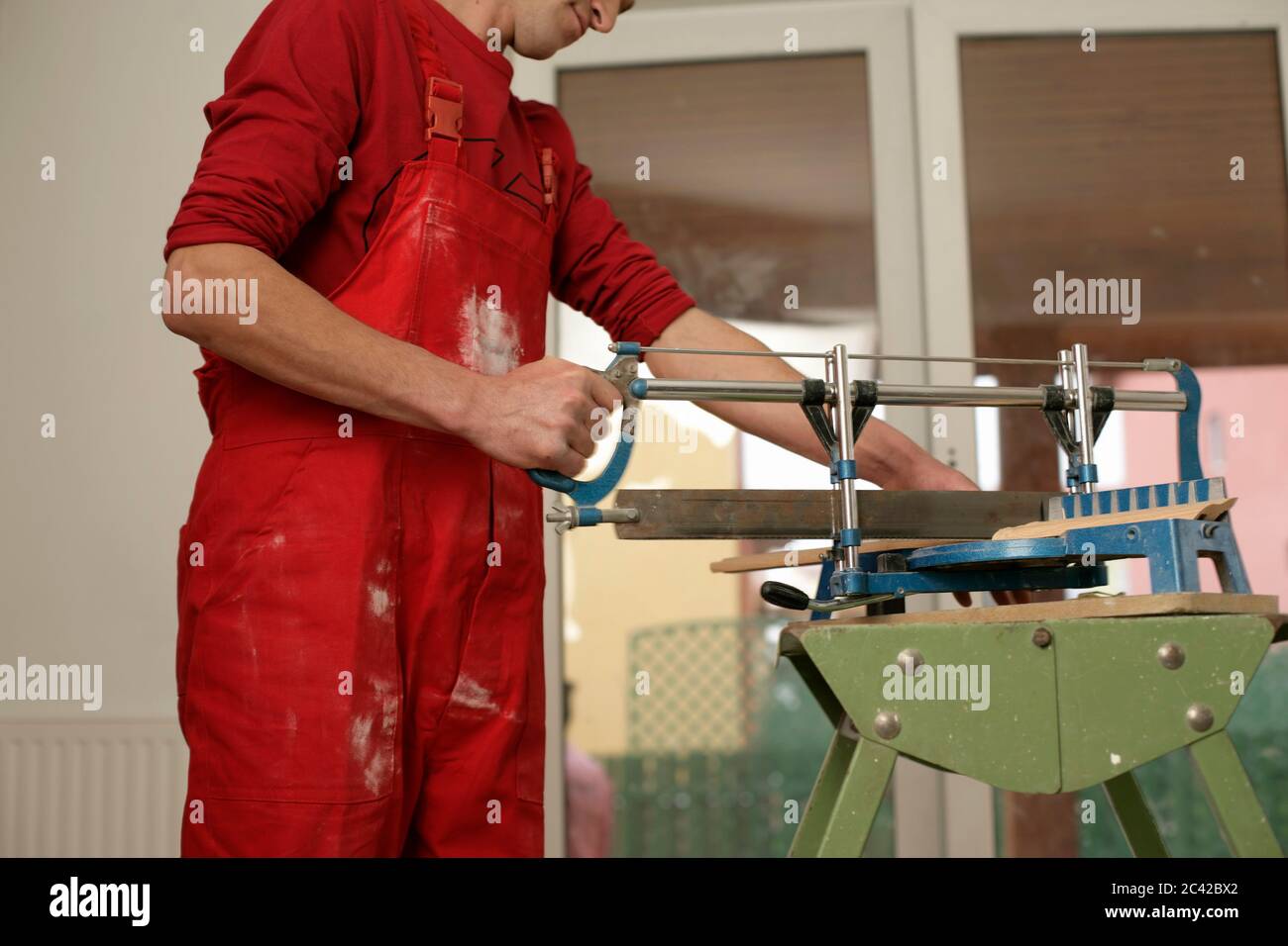 Man in a red work suit saws a hallway suitably - artisan - sawhorse ...