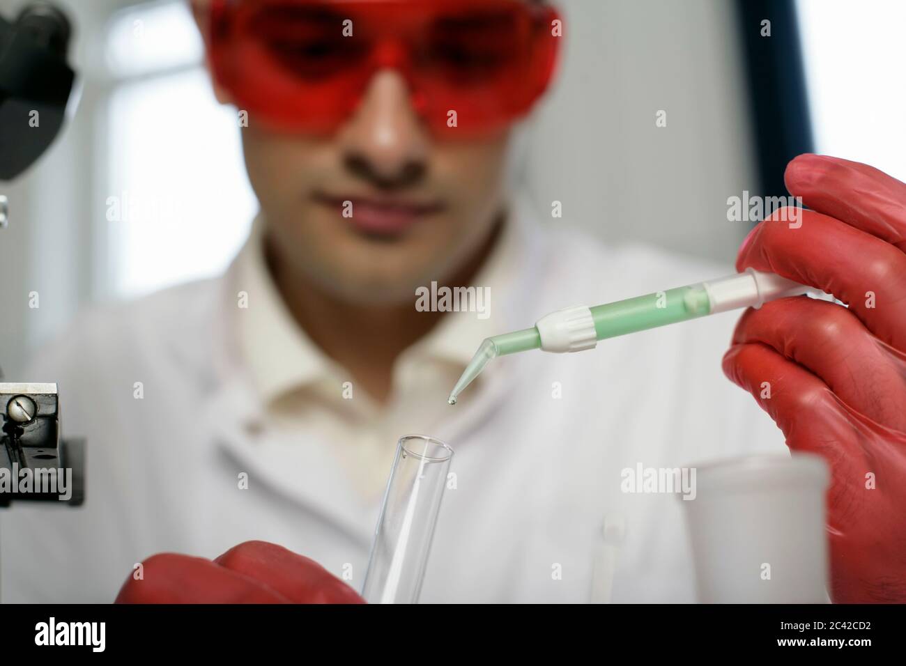 Laboratory worker puts a liquid into a test tube using a piston ...