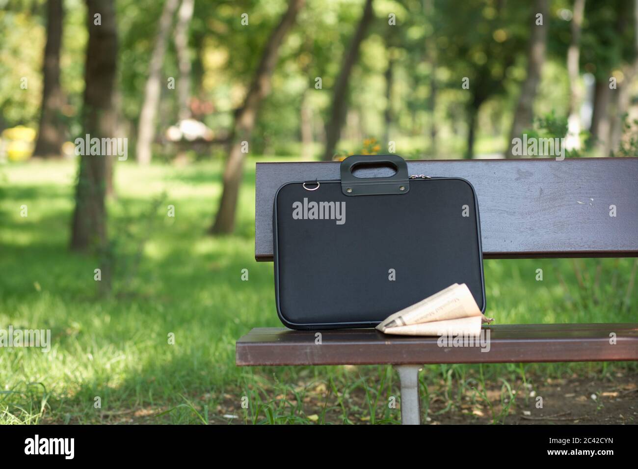 Briefcase and newspaper on a bench Stock Photo - Alamy
