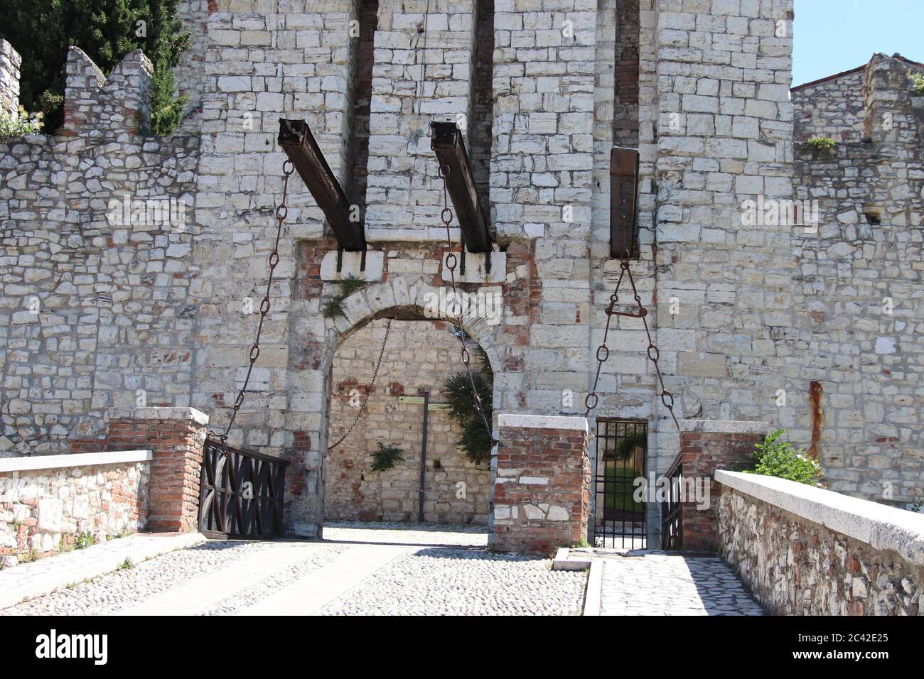 Stone wall with merlons and drawbridge gate of medieval castle of ...