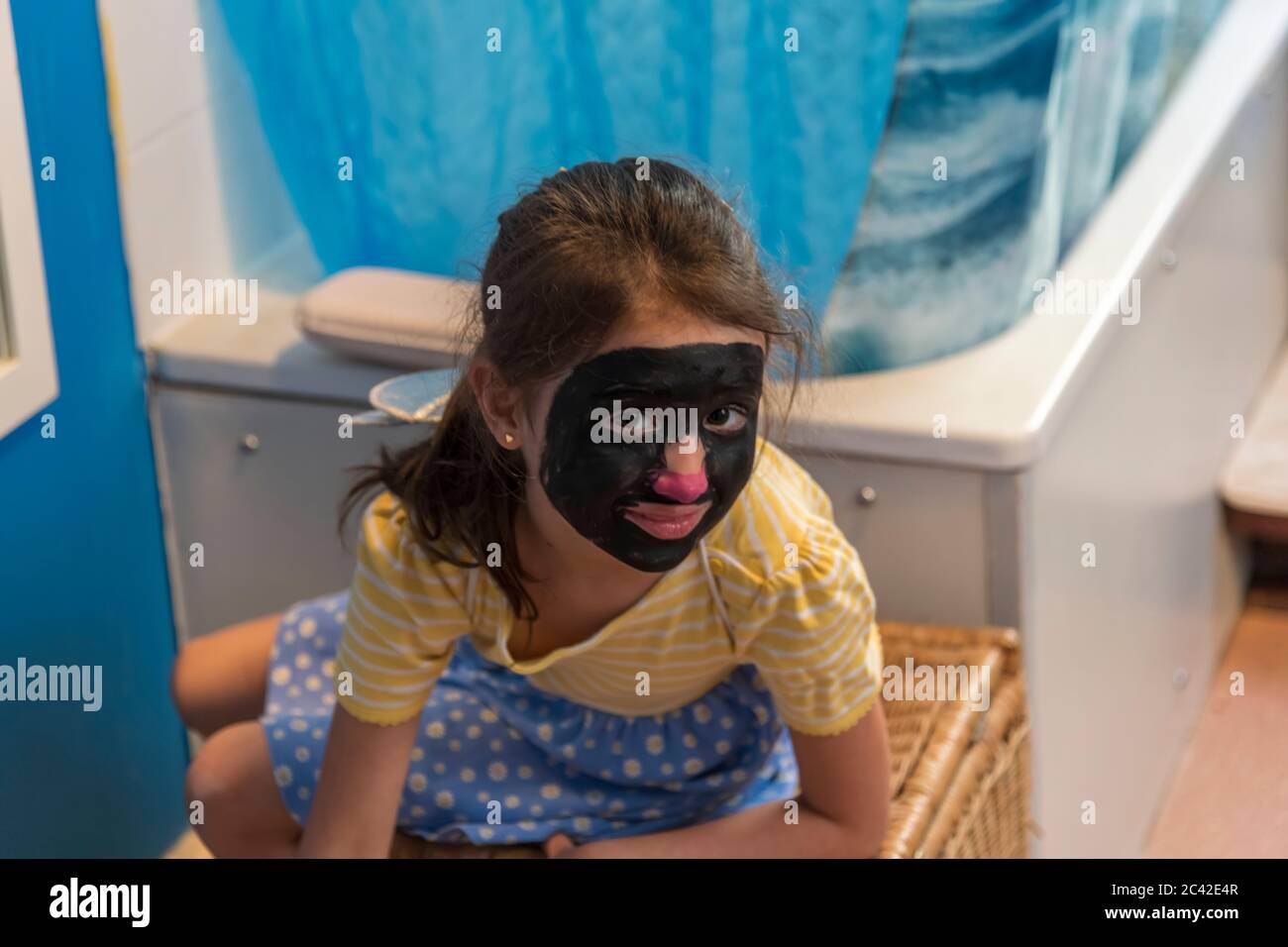 A young girl from poor deprived family is entertaining herself by face ...