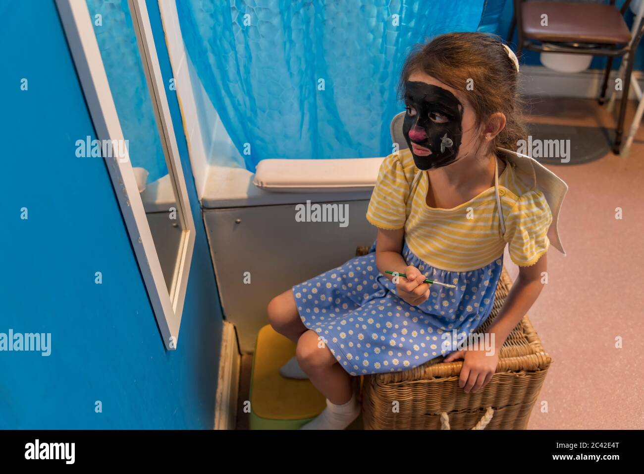 A young girl from poor deprived family is entertaining herself by face ...