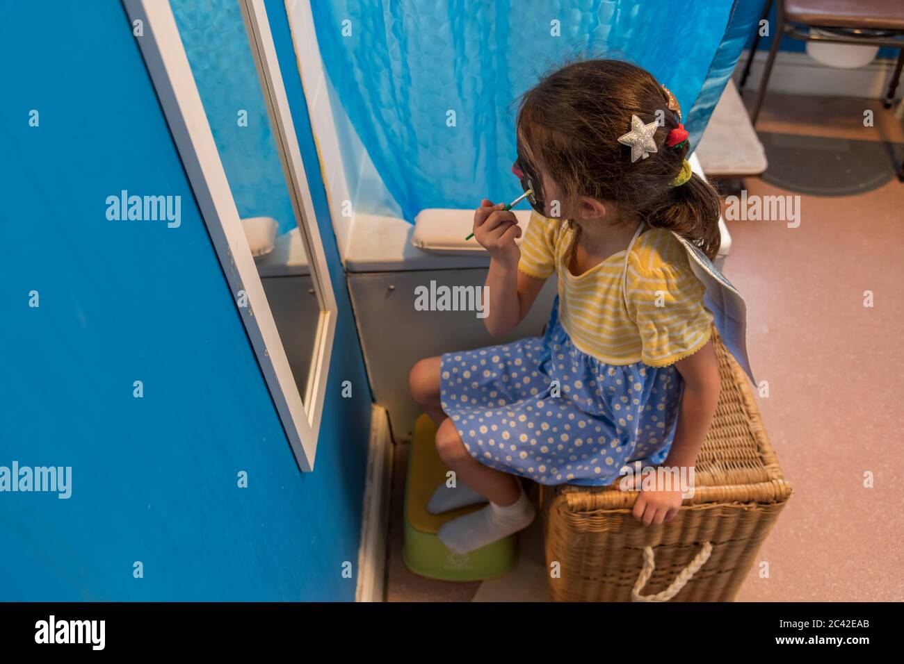 A young girl from poor deprived family is entertaining herself by face ...