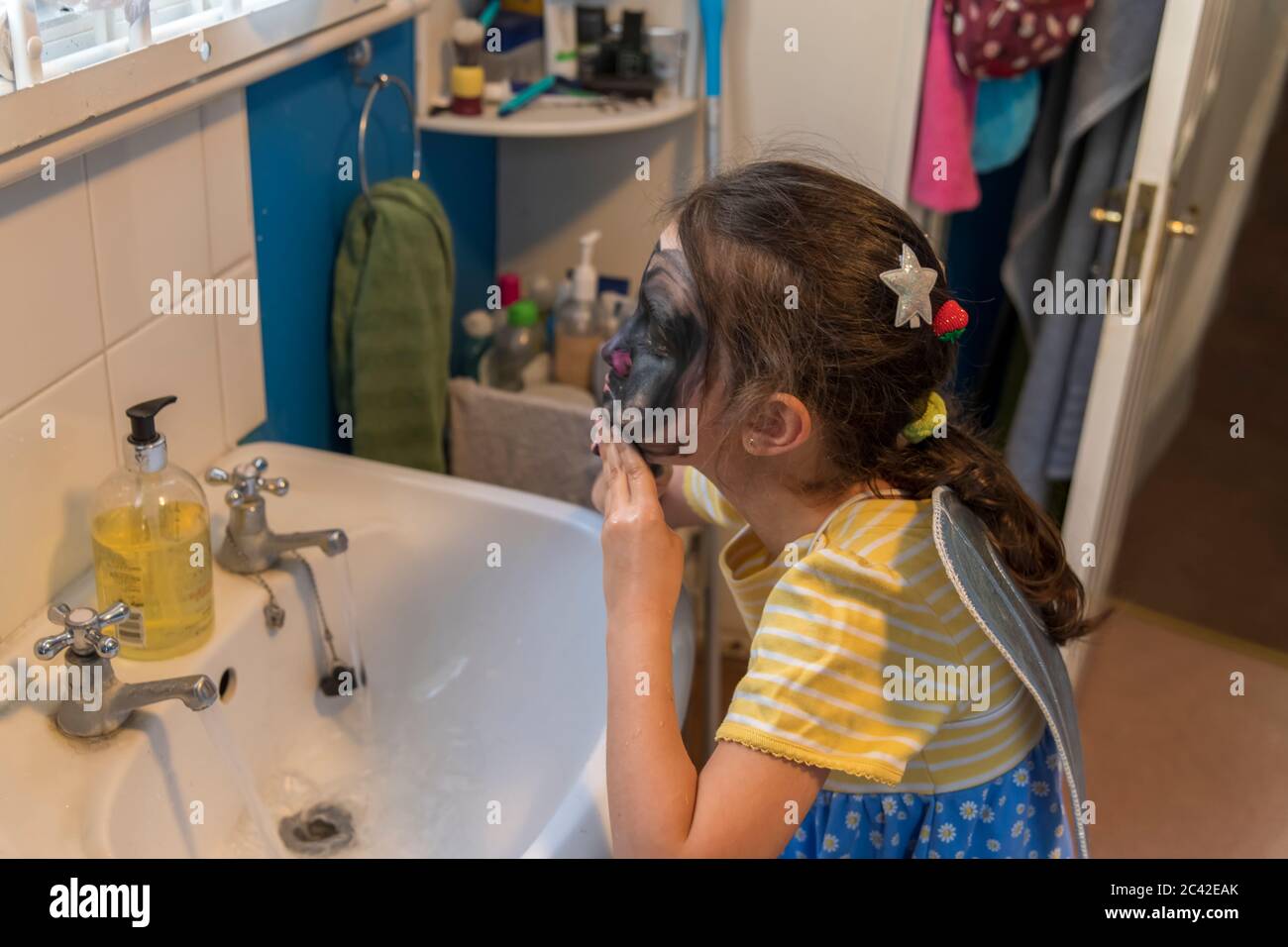 A young girl from poor deprived family is entertaining herself by face ...