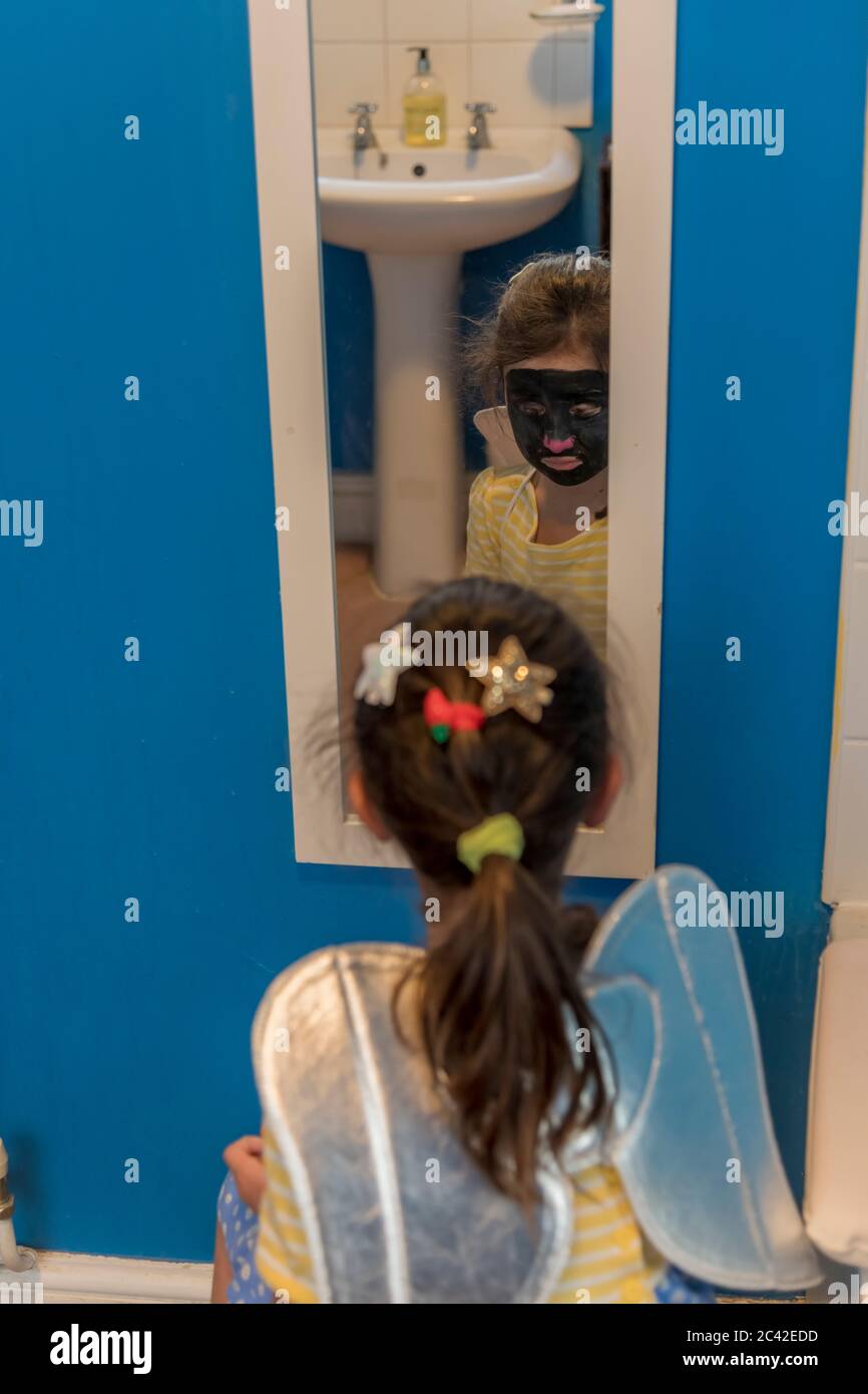 A young girl from poor deprived family is entertaining herself by face ...