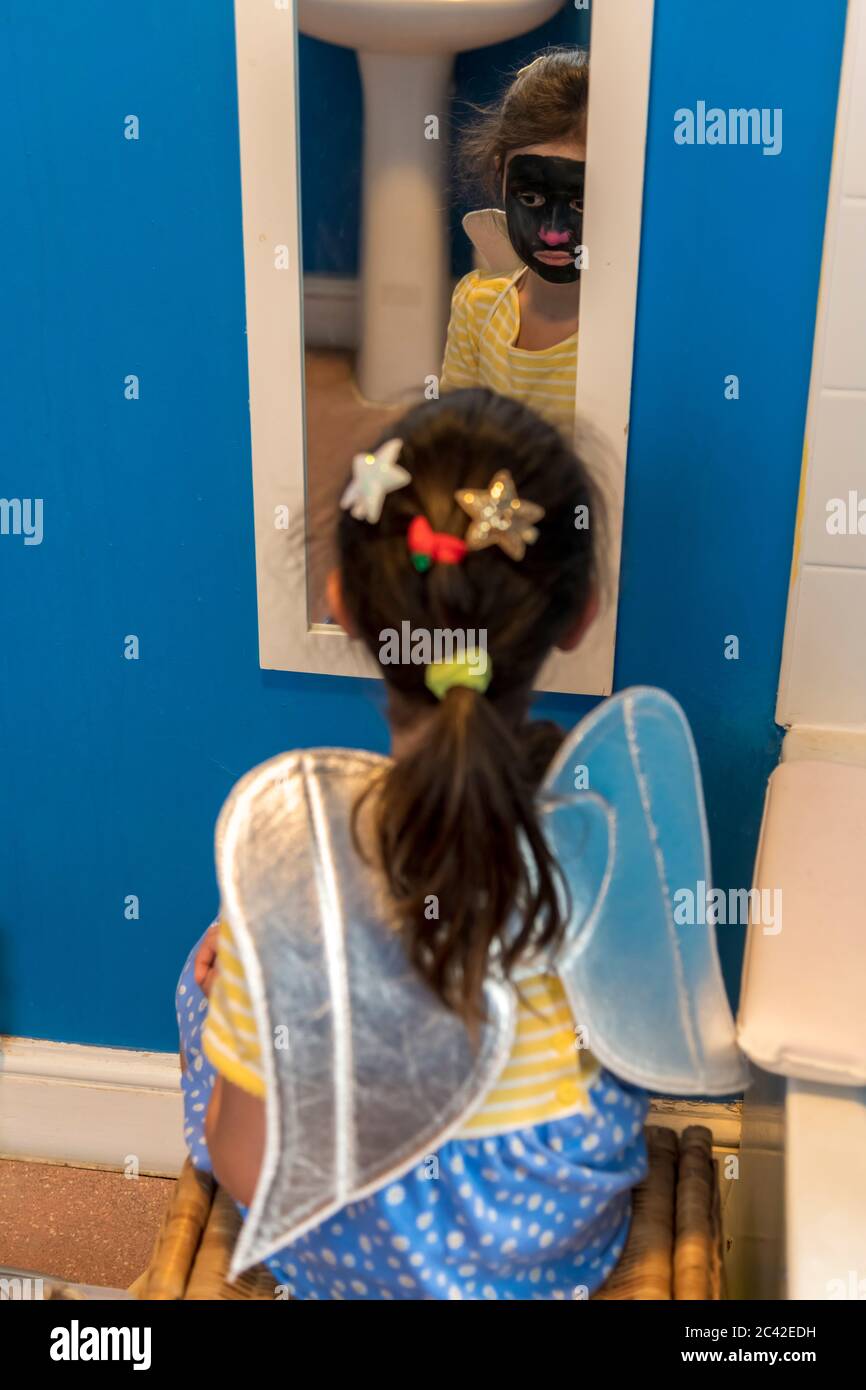 A young girl from poor deprived family is entertaining herself by face ...