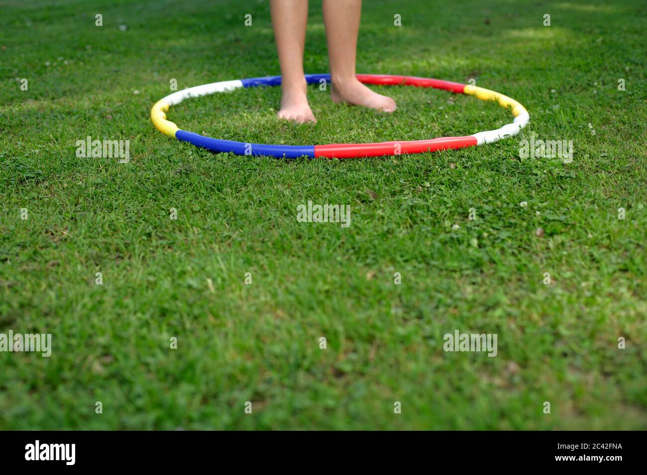 Girl stands in a hula hoop on grass Stock Photo - Alamy