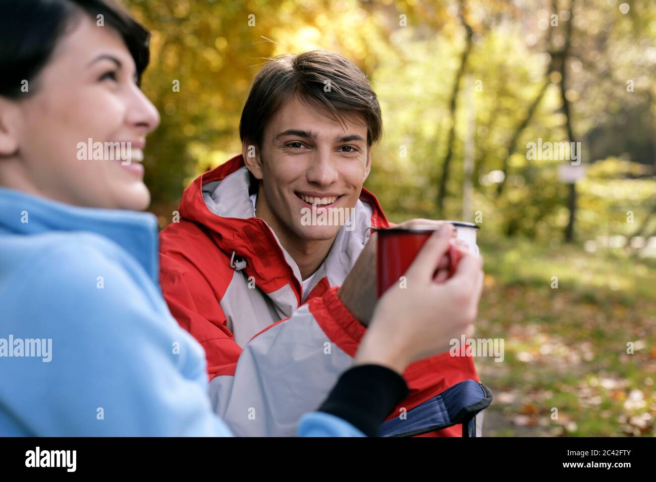 A smiling couple is sitting in the forest and drinking coffee Stock ...