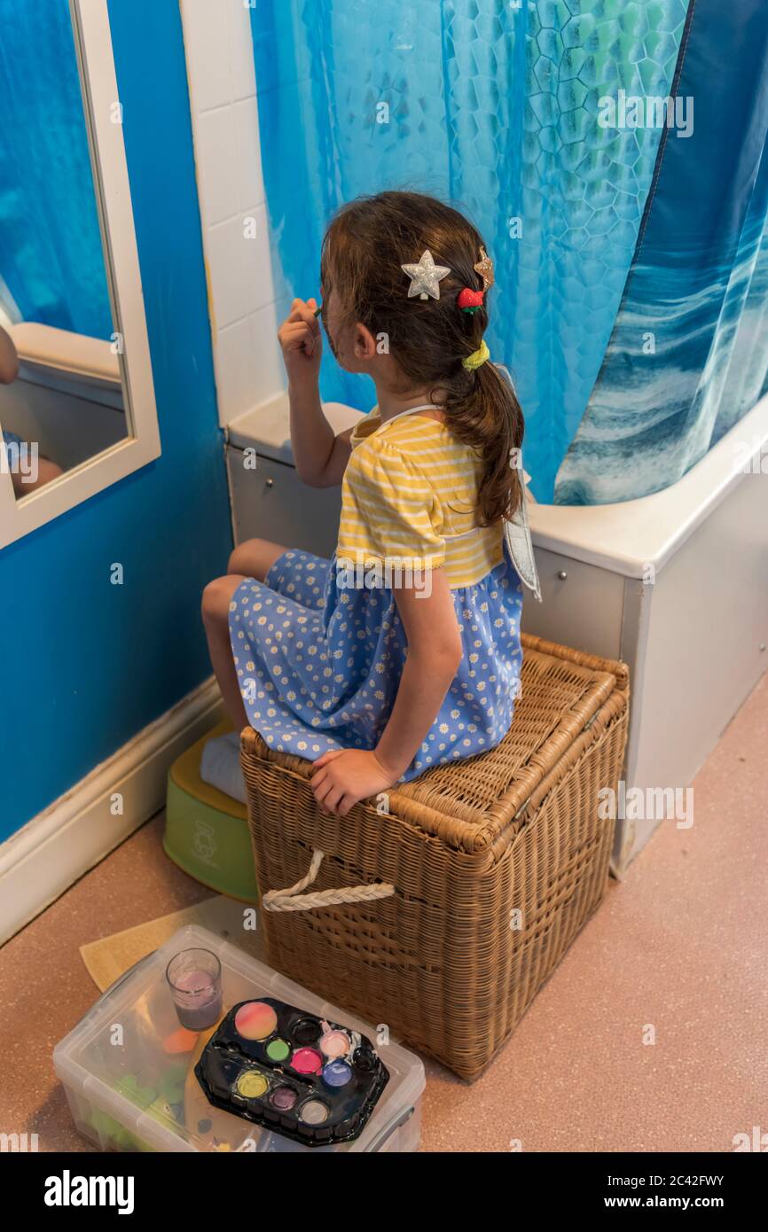 A young girl from poor deprived family is entertaining herself by face ...