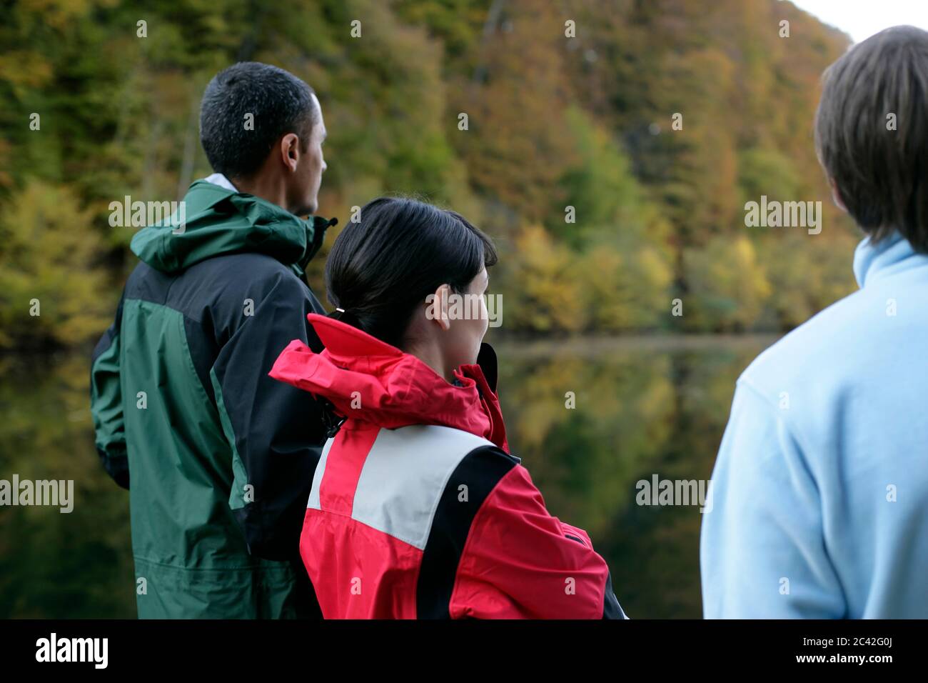 Two men and a woman look out over a lake Stock Photo - Alamy