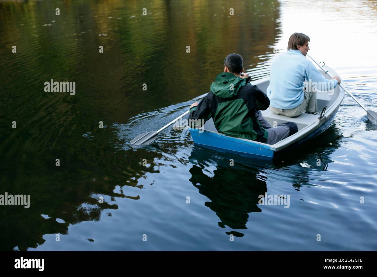Two men paddle in a boat across a lake Stock Photo - Alamy