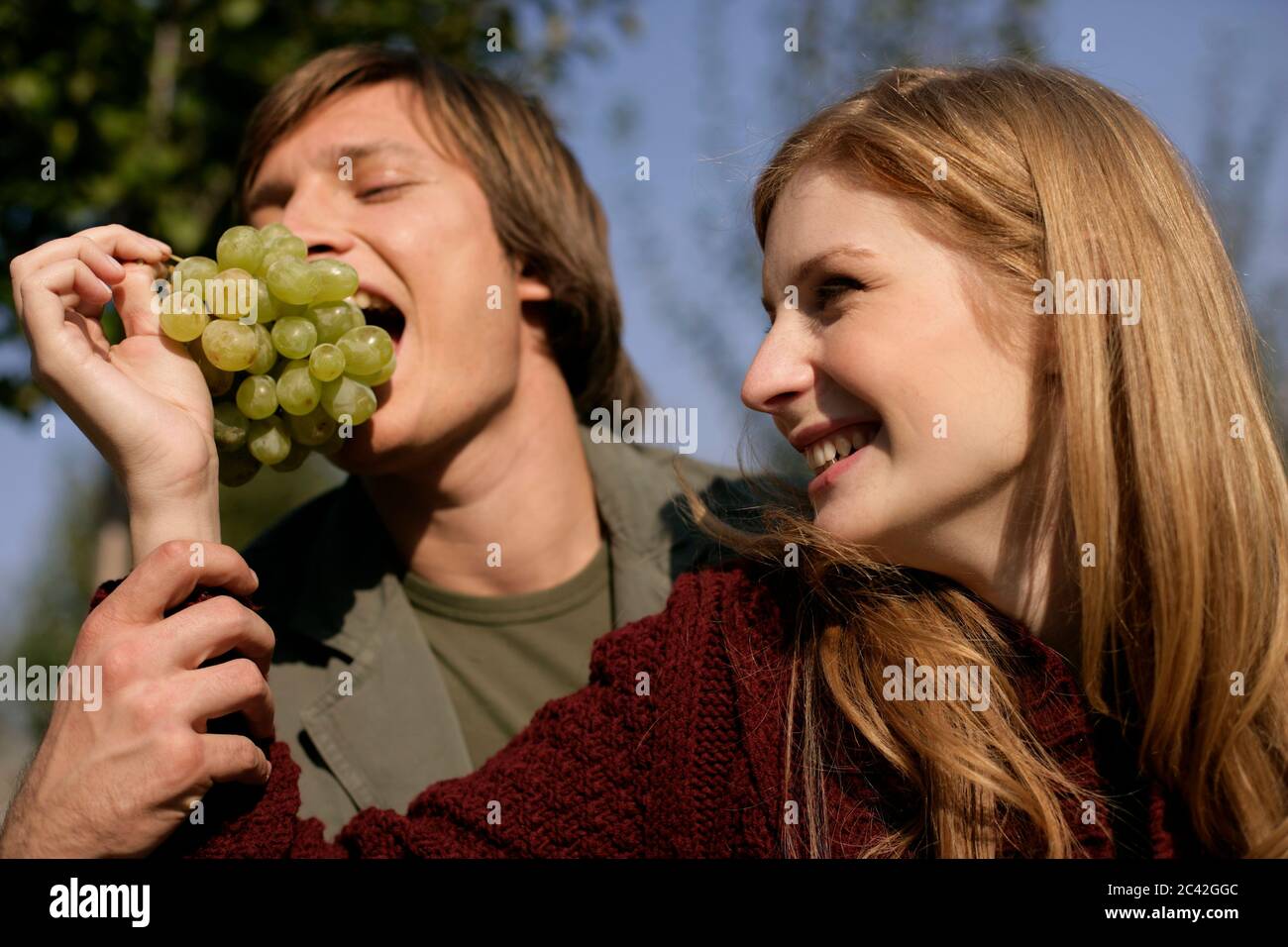 Woman hands man grapes to eat Stock Photo - Alamy