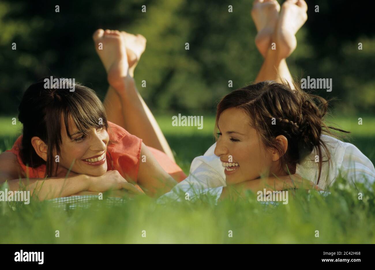 Two girlfriends lie face down on a meadow - talking - park - friendship ...