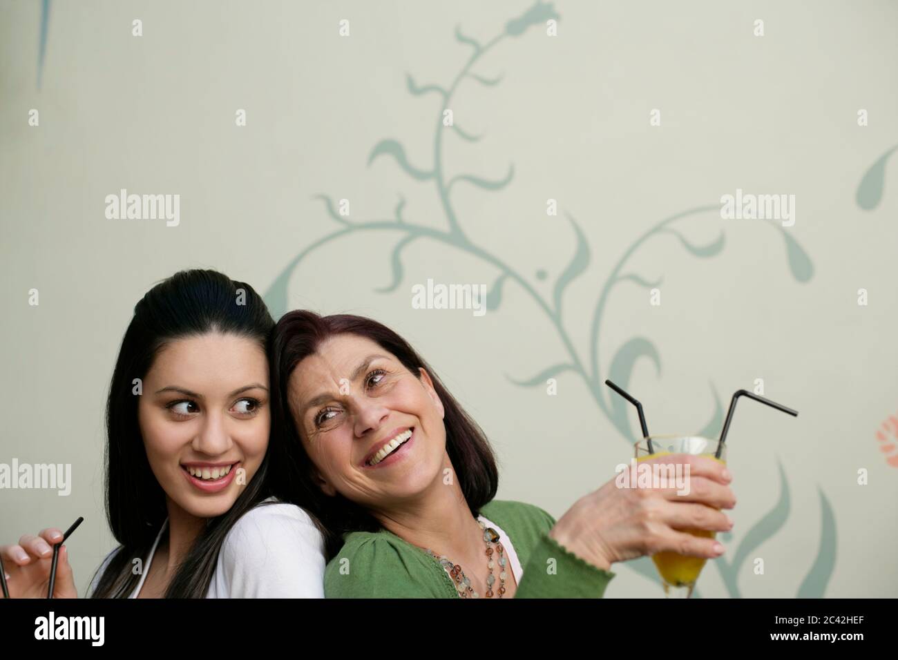 Mother and daughter sit back to back Stock Photo - Alamy