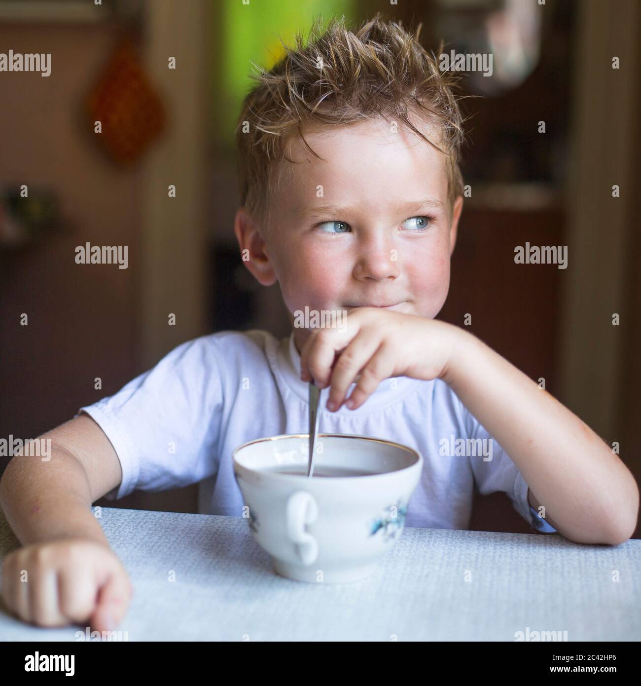 Funny little boy is drinking tea at the table in home Stock Photo - Alamy