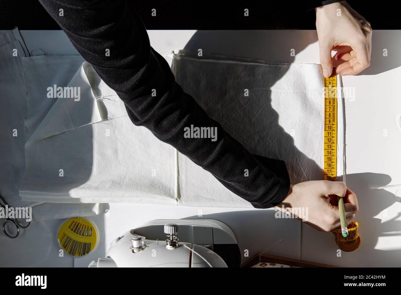 Top view of tailor working at table with sewing machine and marking ...