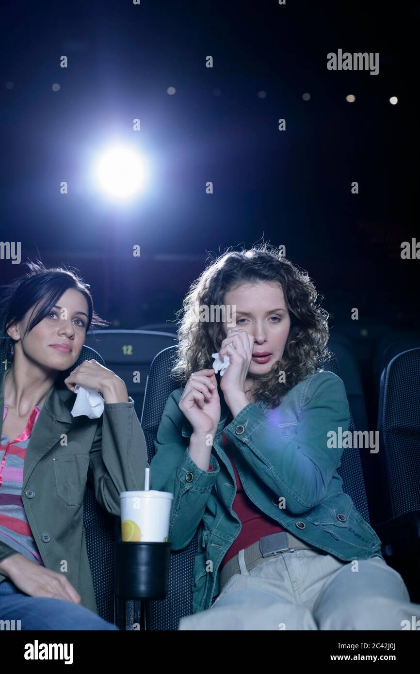 Two young women sit crying in the cinema Stock Photo - Alamy