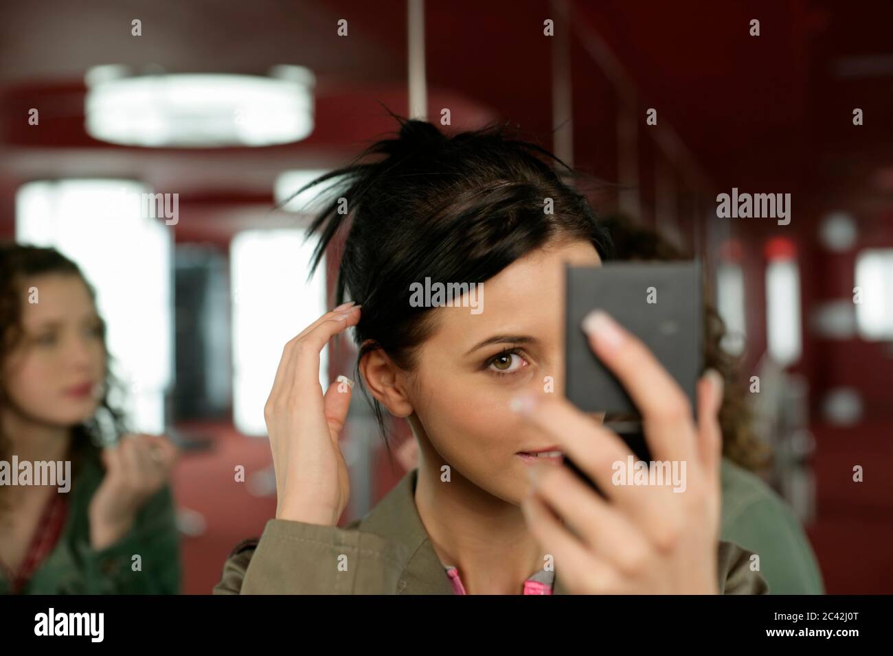 Young woman looks at herself in the hand mirror Stock Photo - Alamy