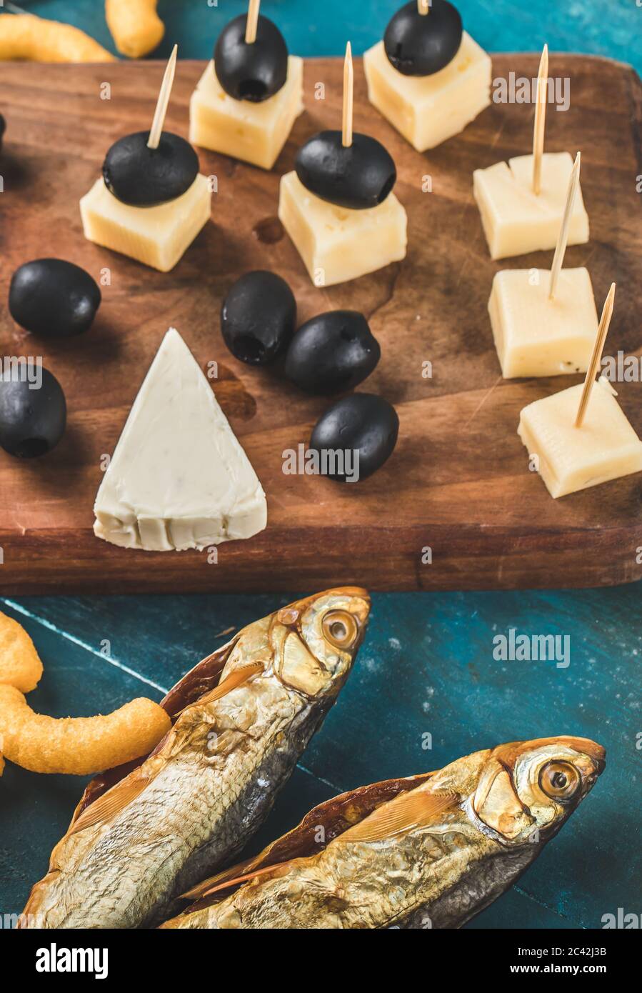 Snack board with cheese cubes and dry fish Stock Photo - Alamy