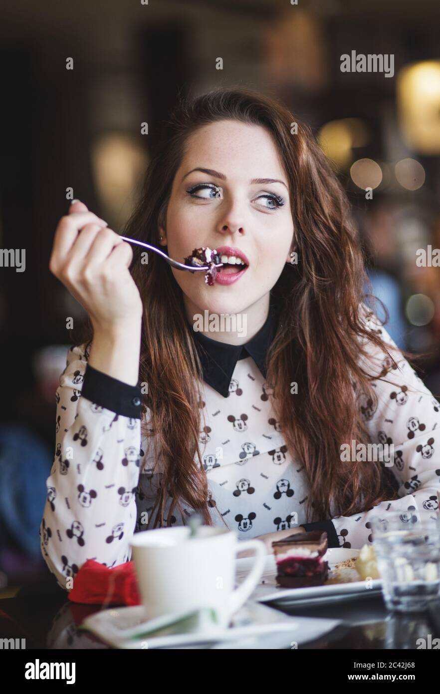 Portrait of young woman eating cake Stock Photo - Alamy