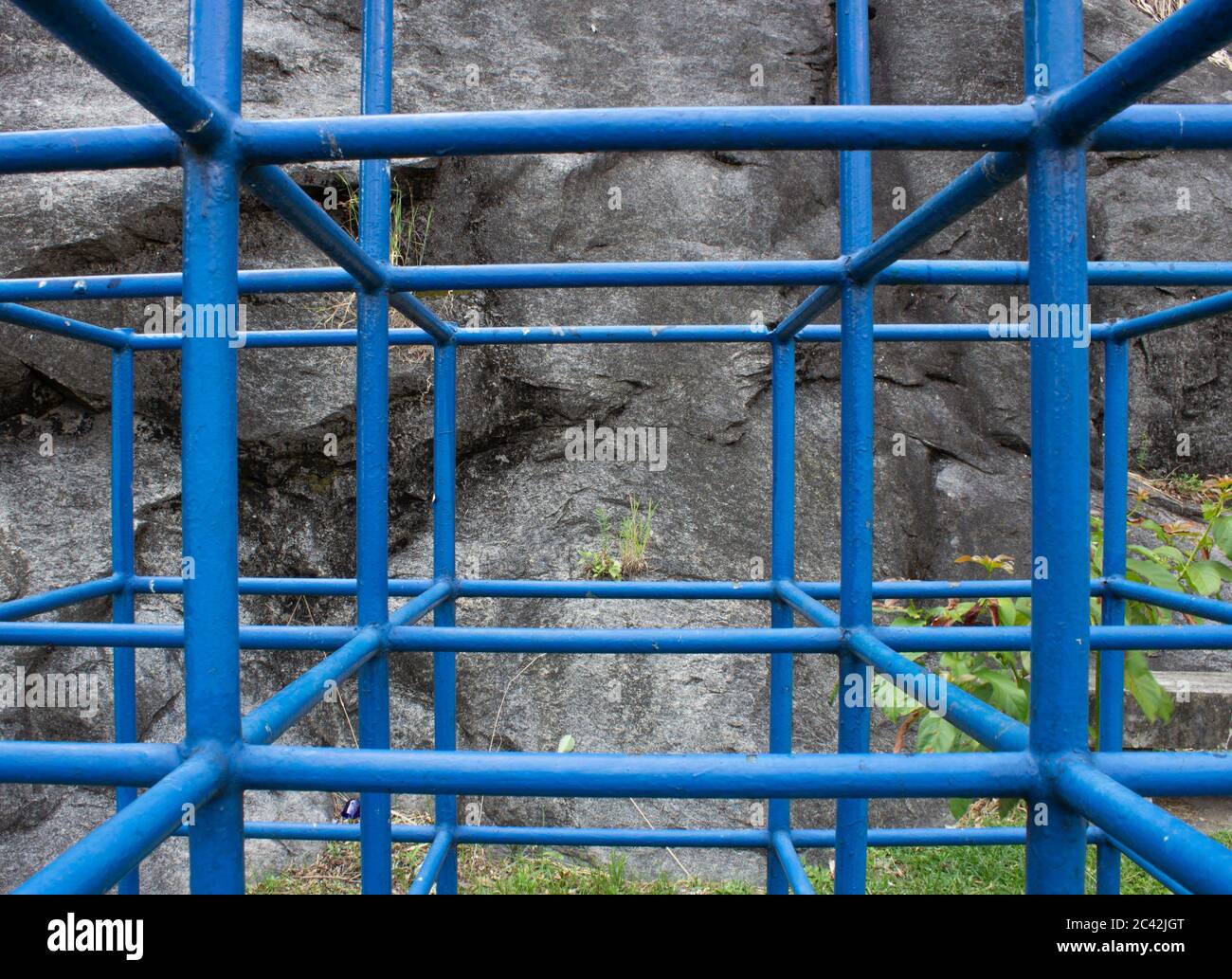 A cage structure for kids do play with, next to a rock wall Stock Photo ...