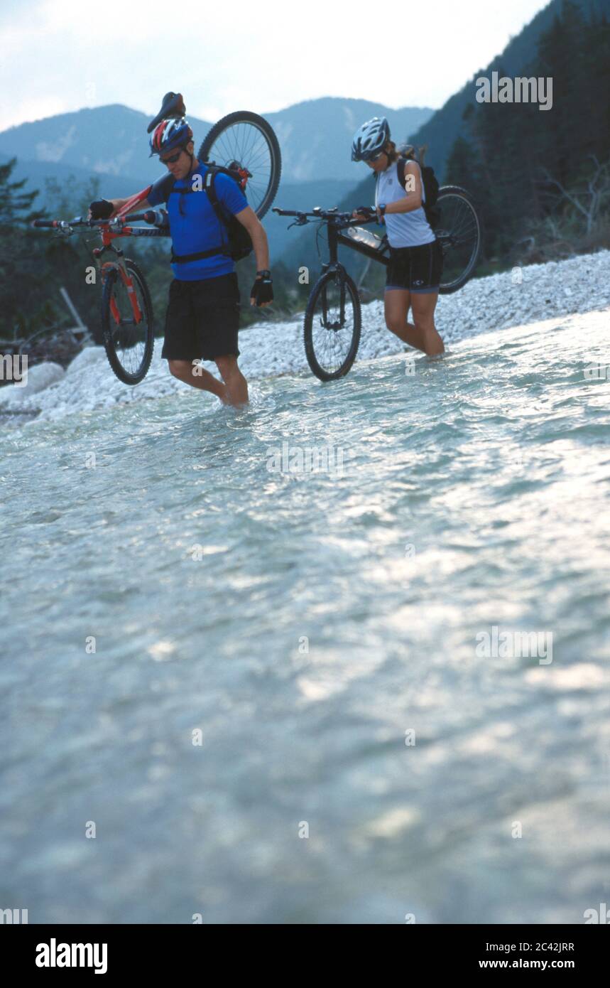 Mountain bikers wade their bikes through Bach - mountain biking Stock ...