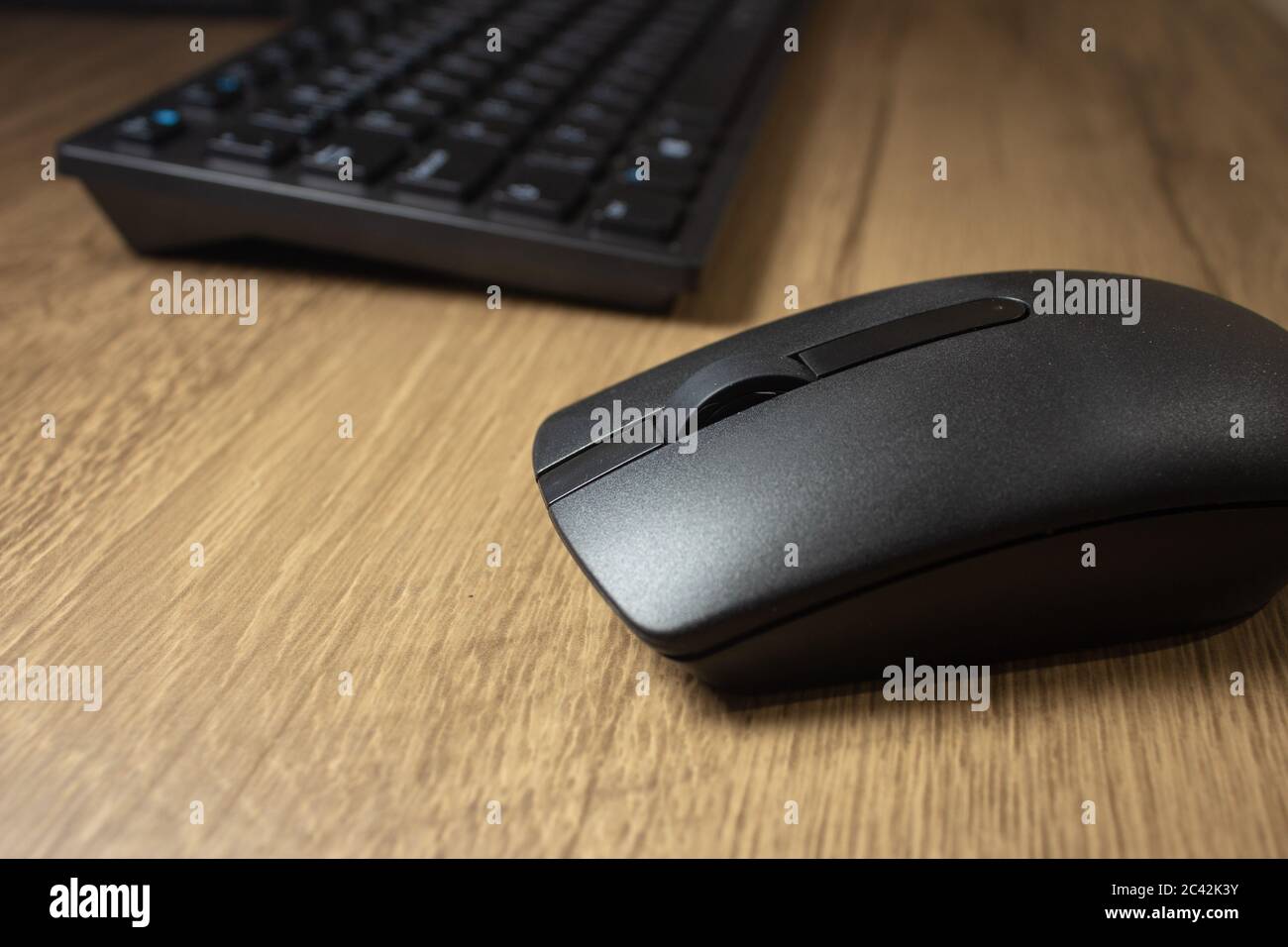 Wireless mouse and keyboard set on top of a wooden office desk, on a ...