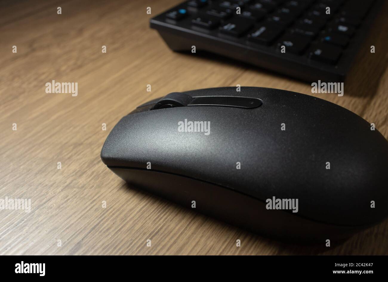 Wireless mouse and keyboard set on top of a wooden office desk, on a ...