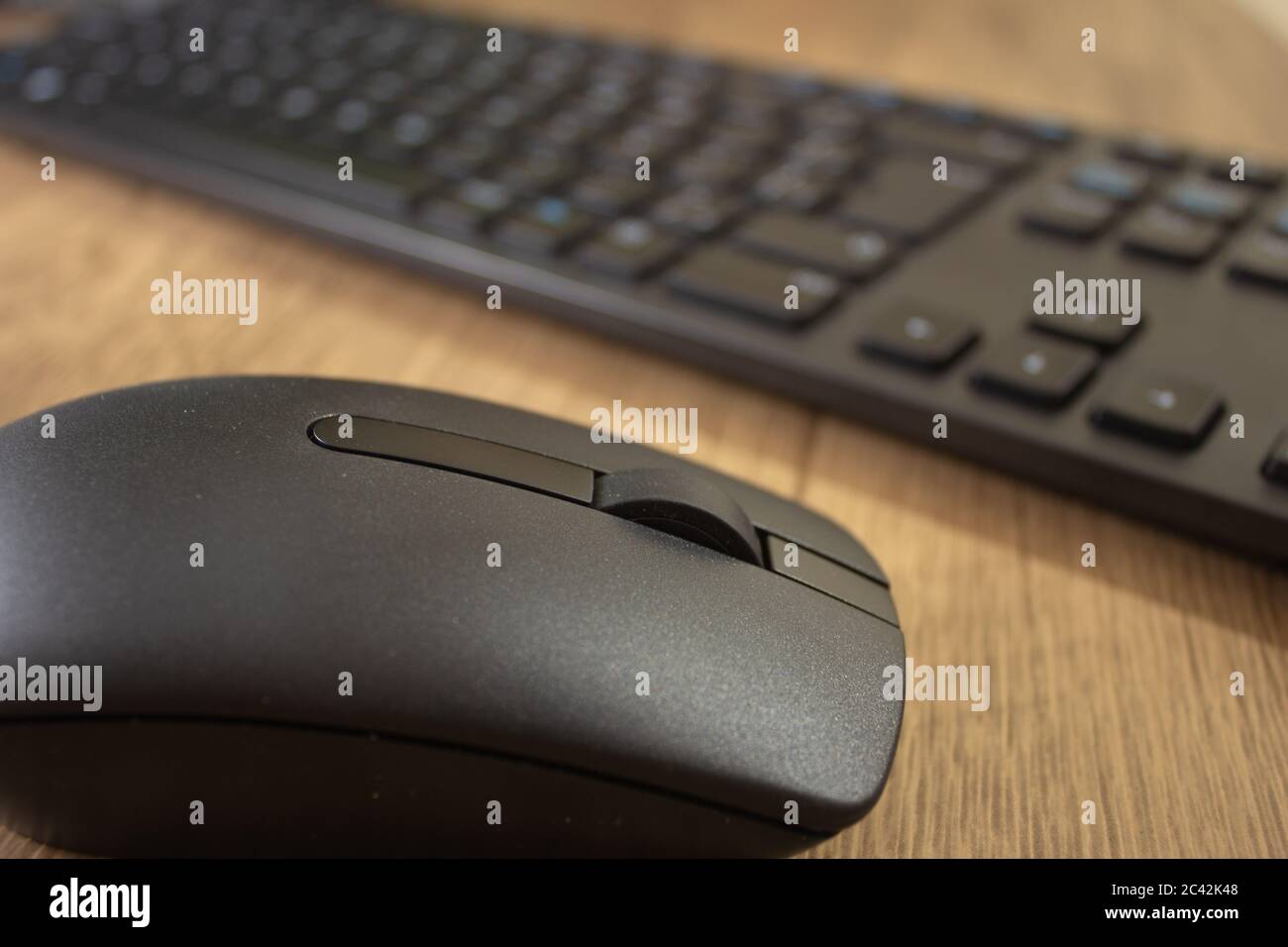 Wireless mouse and keyboard set on top of a wooden office desk, on a ...