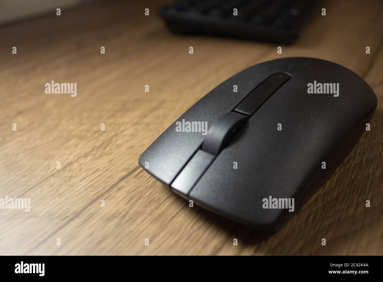 Wireless mouse and keyboard set on top of a wooden office desk, on a ...