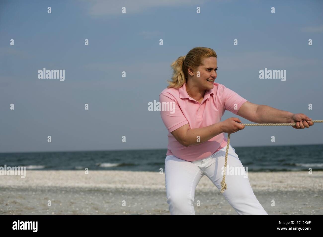 Blonde chubby woman pulling on a string - beach Stock Photo - Alamy