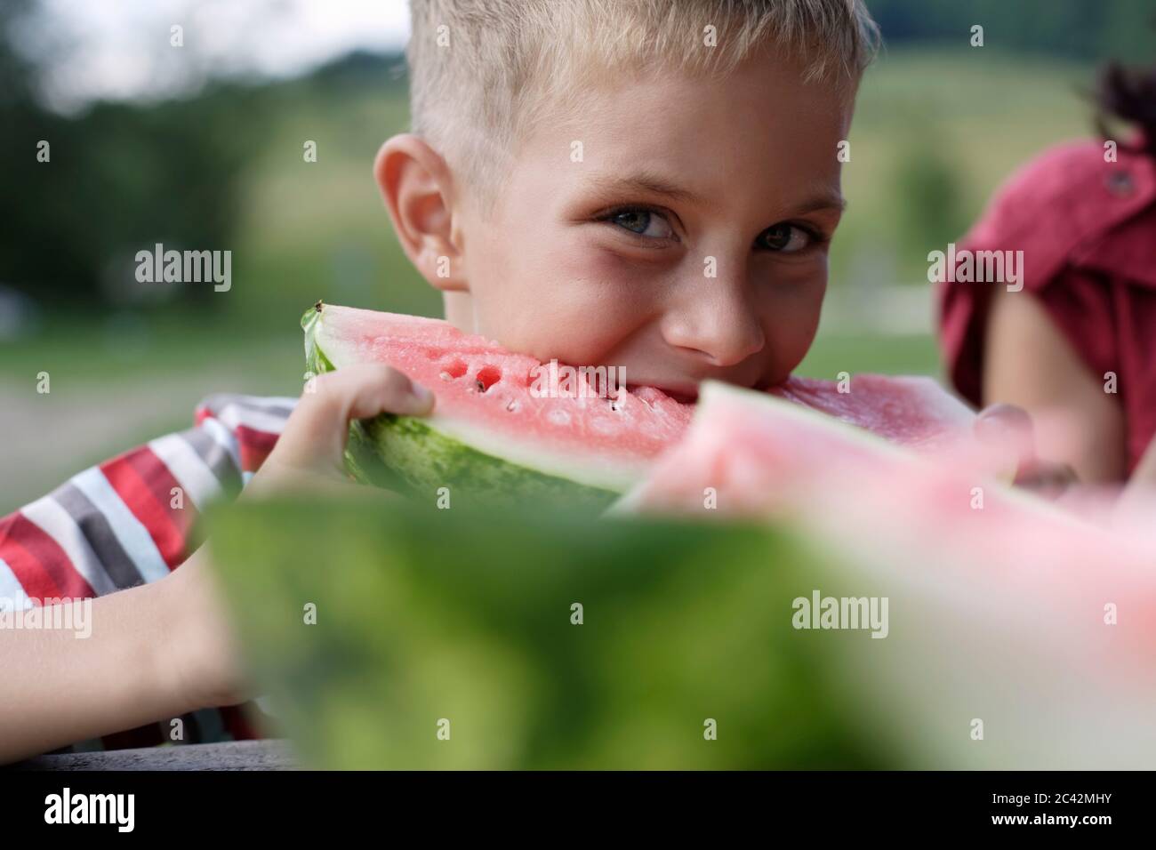 Boy bites into a large piece of watermelon - fruit Stock Photo - Alamy
