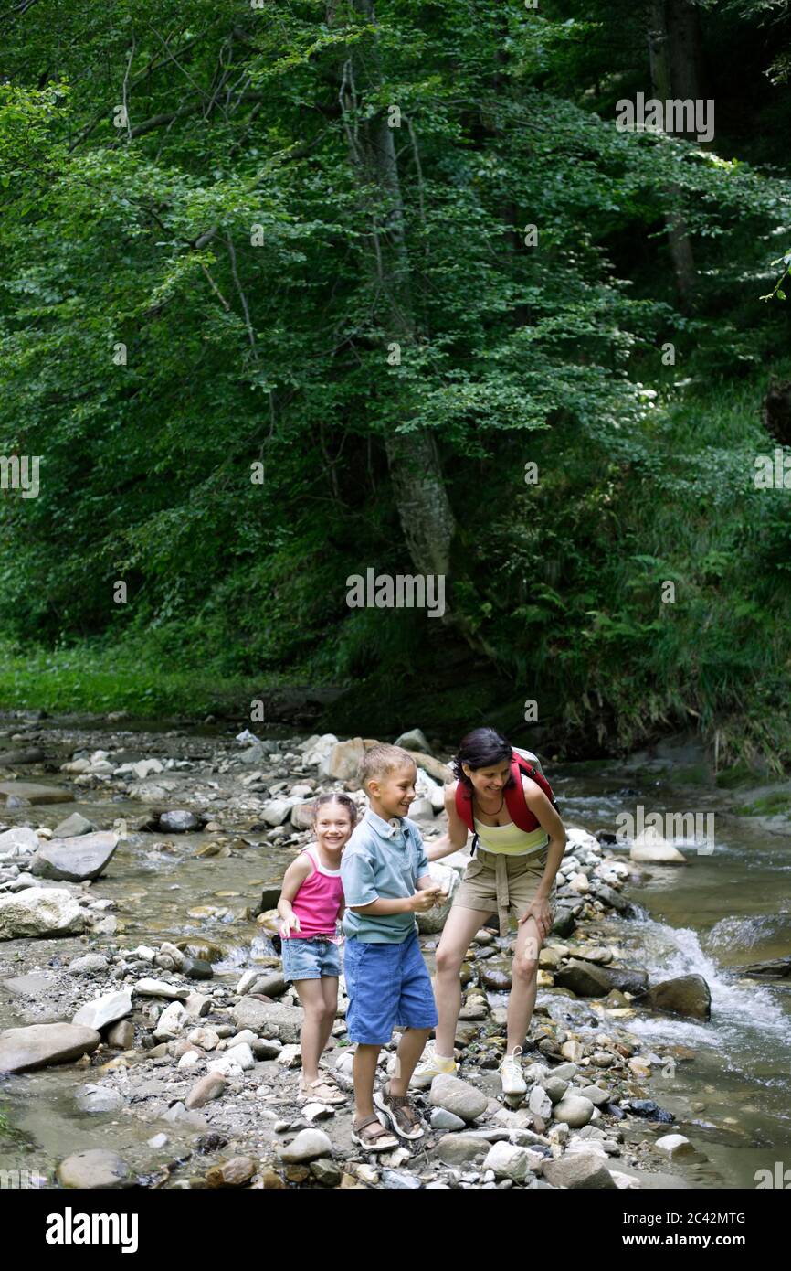 Two children collect stones next to their mother - excursion - river ...