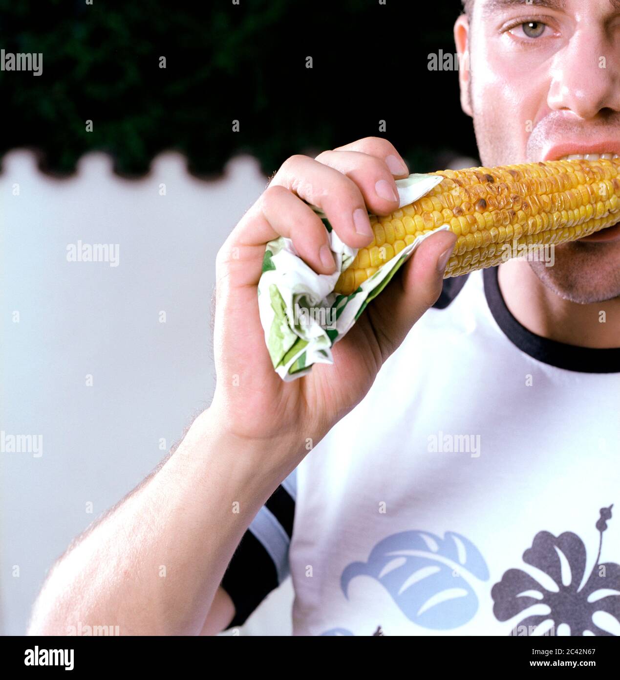 Young man (sliced) eats corn on the cob - grill party Stock Photo - Alamy