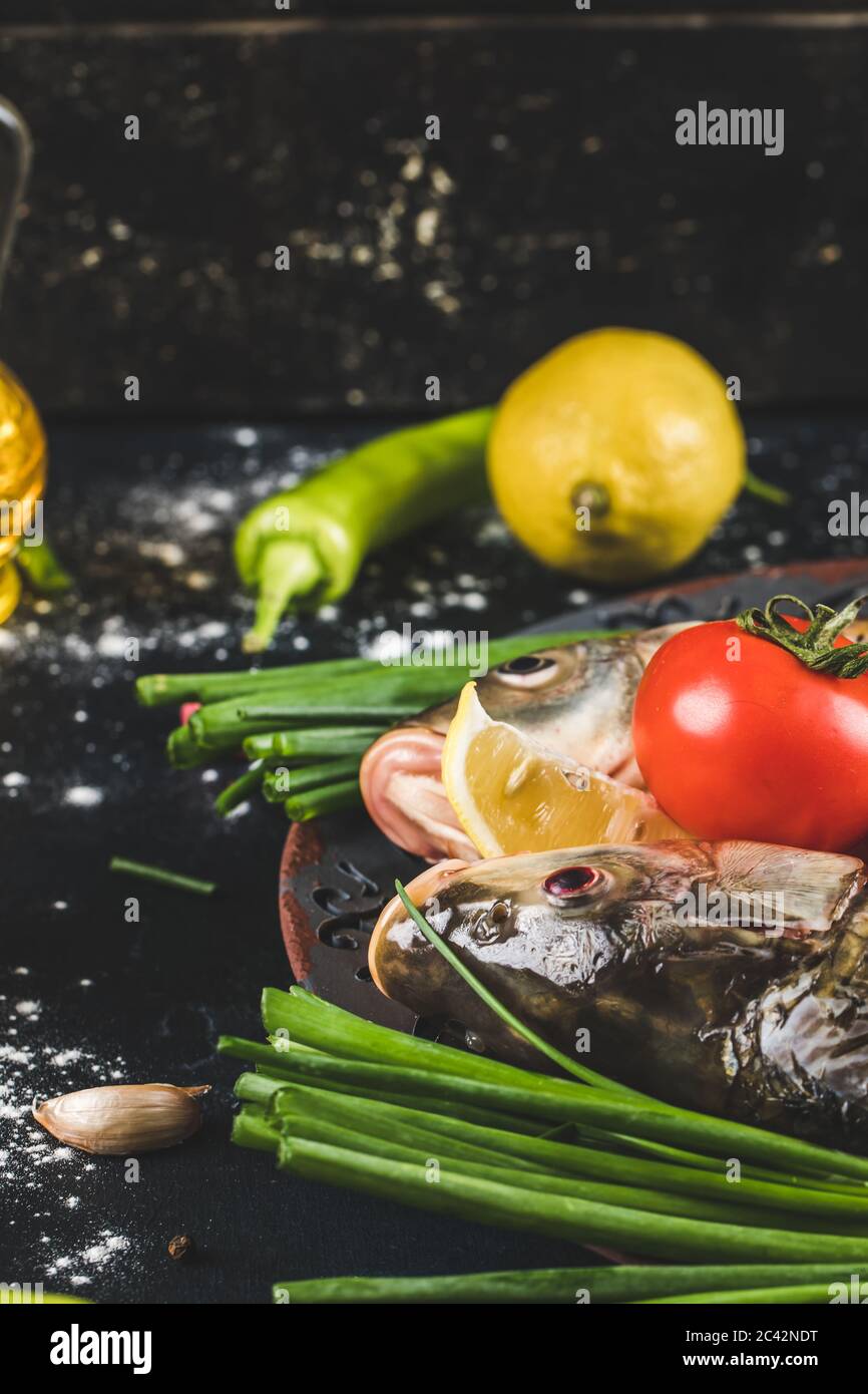 Raw fish heads with greenery, lemon and tomatoes Stock Photo - Alamy